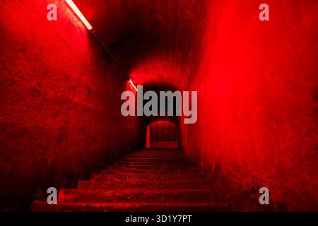 Dark eerie staircase leading to underground space illuminated by red ...