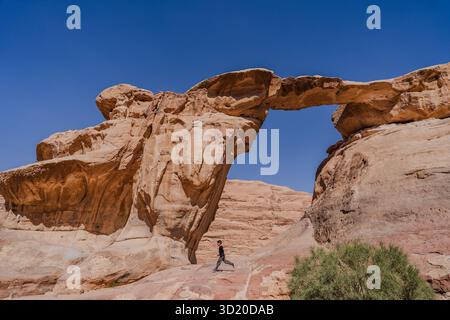 Iconic rock arch rising from the sandstone desert landscape of Wadi Rum ...