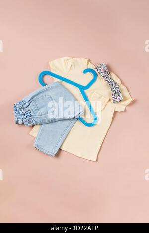 Childish image with jeans and a yellow t-shirt on a pink background ...