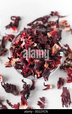 Hibiscus tea and dry hibiscus petals on gray background. Two glass cups of red hibiscus tea on ...