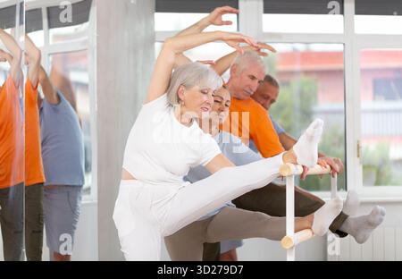 Ballet pose grand batman - elderly women and men at choreography lesson ...