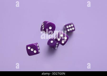 Purple game dices on lilac background Stock Photo - Alamy