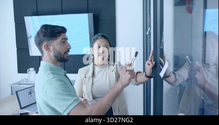 Manager pointing to a glass Board with sticky notes Stock Photo - Alamy