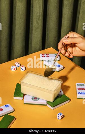 Hand holding a Mahjong tile with a green game table setup in the ...