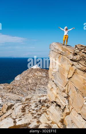 Woman stands on rocky cliff overlooking expansive canyon landscape on a ...