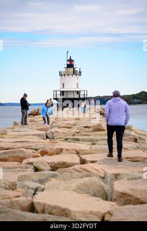 People walk on the stone breakwater of Porto da Barra beach in Salvador ...