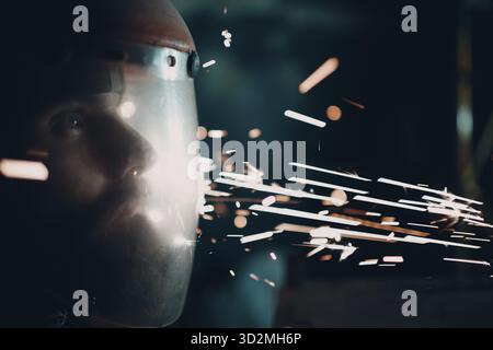 Man welder grinder in transparent protective mask with flying sparks in ...