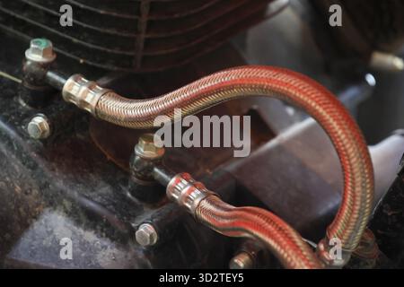 Close up mechanical red braided hose curve over motorcycle engine part ...
