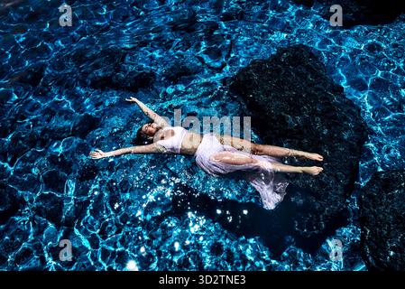 Woman laying in wet dress in creek bed Stock Photo - Alamy