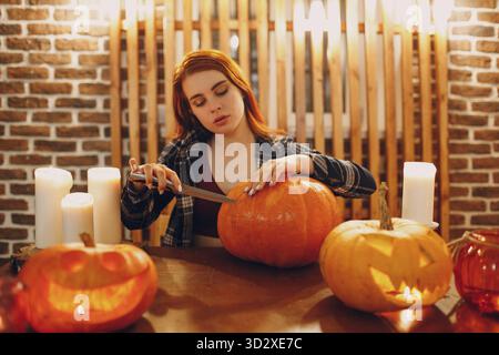 Young woman making Halloween pumpkin Jack-o-lantern with candles in ...
