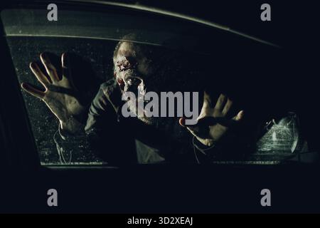 Zombie male attack car driver through vehicle window glass halloween ...
