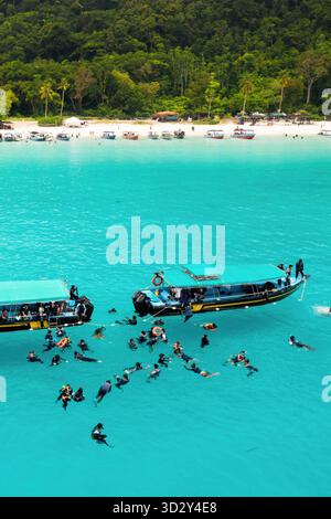 A boat parked in the crystal clear sea with a mountain in the ...