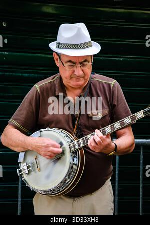 Senior happy man plays acoustic guitar while sitting on sofa in room ...