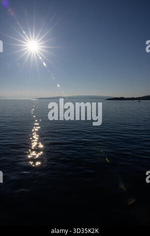 bright clear blue skies over a rocky beach with driftwood Stock Photo ...