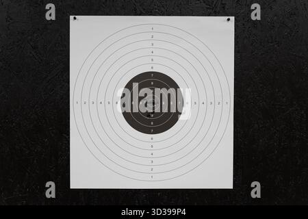 Paper target with tight bullet holes group hanging on wooden bullet ...