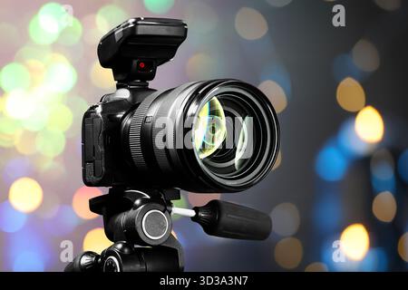 Professional camera against blurred lights on light blue background ...