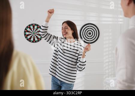 Woman and her colleagues playing darts in office Stock Photo - Alamy
