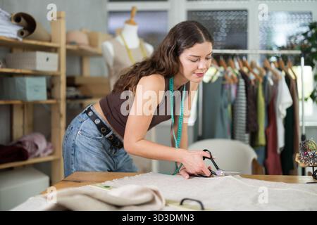 Female dressmaker cutting fabric into pattern pieces in workshop Stock ...