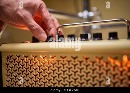 A musician is adjusting the amplifier settings for optimal sound ...