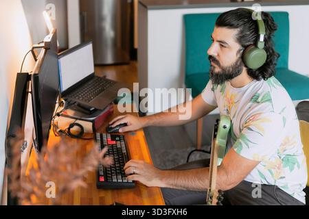 Image of focused man in headphones playing video game on computer while ...