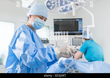 Surgical team in blue medical suits using medical instruments and ...