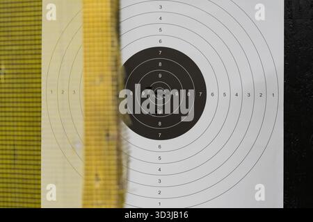 Paper target with tight bullet holes group hanging on wooden bullet ...