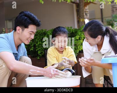 Happy family of three doing pottery together outdoors high quality ...