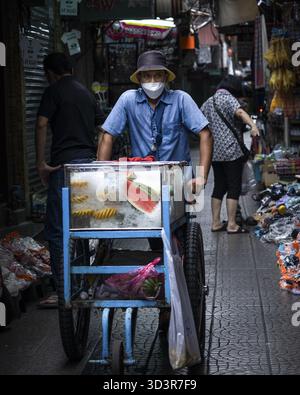 Man pushing shopping cart through supermarket aisle while buying ...