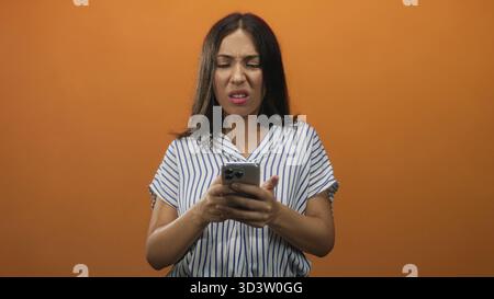 Disgusted young woman holding mobile phone with blank screen on pink ...