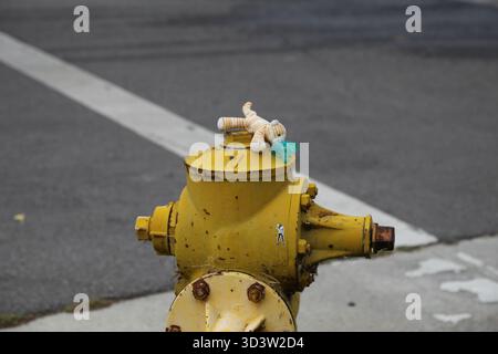Yellow fire hydrant with small lost toy figure on top in urban street ...