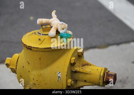Yellow fire hydrant with small lost toy figure on top in urban street ...