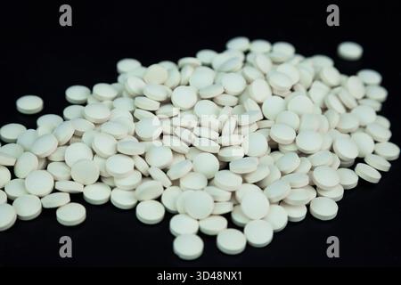 Heap of white pills on colored background. Tablets scattered on a table ...