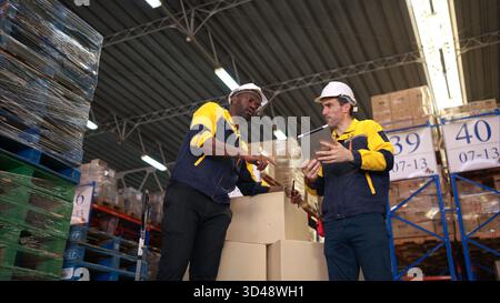 Two warehouse workers are reviewing the list of items based on the ...