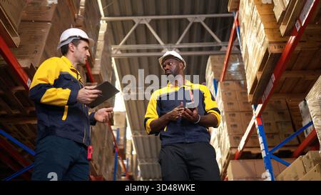 Two warehouse workers are reviewing the list of items based on the ...