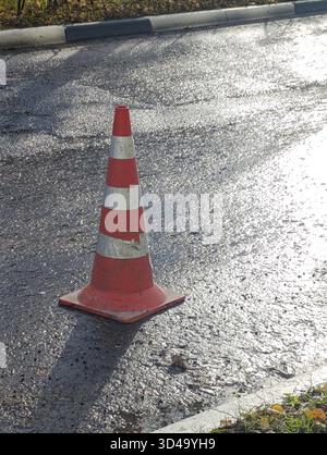 an orange cone stands on a dangerous section of the road. the ...
