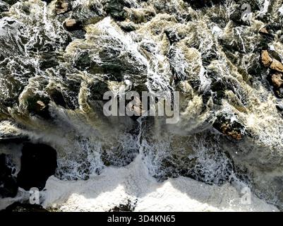 Dynamic stream water with frothy rapids, reflecting sunlight and ...