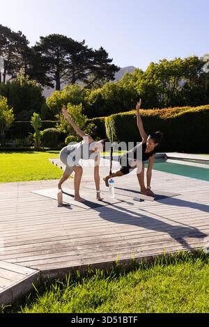 Young friends stretch on their yoga mats at sunset in a forest ...