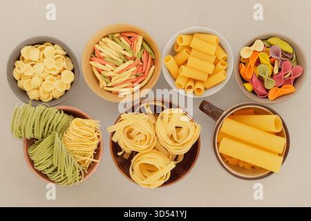 Bowls with different types of uncooked pasta on wooden background Stock ...