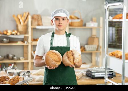 Bakery male employee holds ready made bread of bread in hands Stock ...