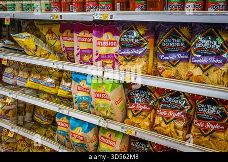 Grocery store aisle with shelves of chips and crackers, sale tags, and ...