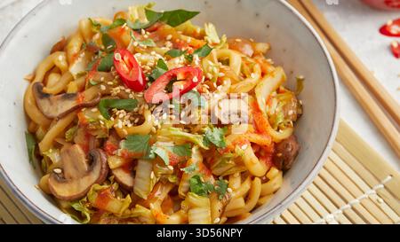 Bowl of stir-fried udon noodles with shrimps and vegetables on wooden ...