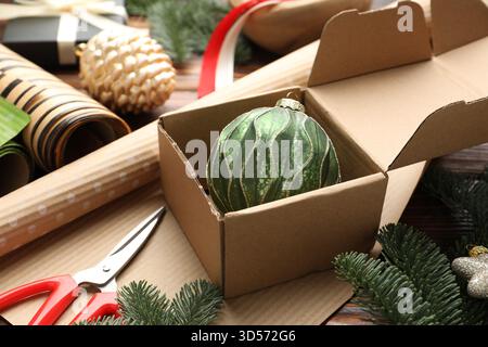 Festive packaging. Box with bauble, scissors, wrapping paper and ...