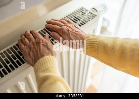A woman is warming her hands by the radiator as the cost of heating is ...