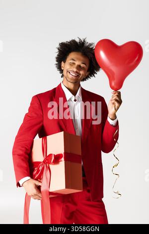 Handsome man with heart-shaped balloon on light background. Valentine's ...