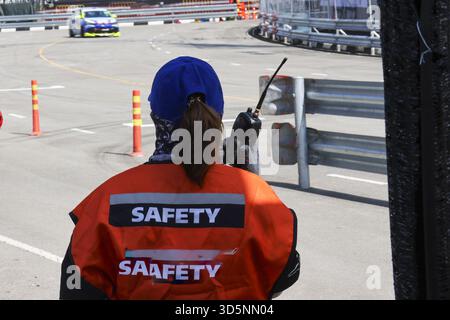 Professional safety marshal in an orange vest attentively watching race ...