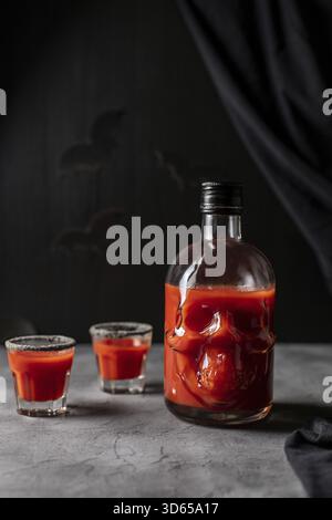 Tomato cocktail in a skull-shaped bottle and glasses. Drink for ...