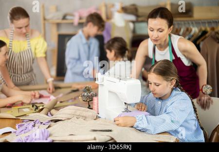 Preteen girl sewing on machine during hands-on class for school ...