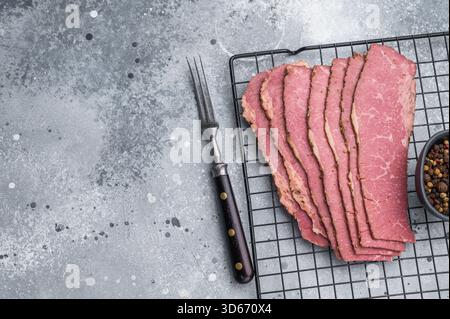 Sliced pastrami arranged on textured ceramic plate against weathered ...