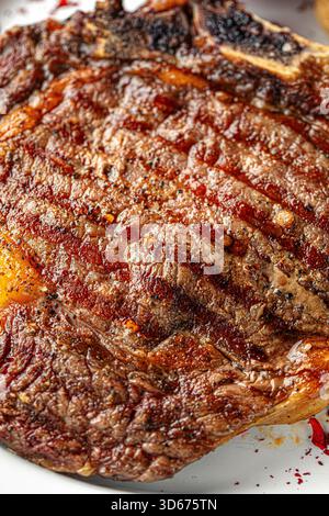 Grilled steak with charred grill marks red peppercorns served on white ...