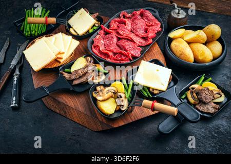traditional authentic swiss raclette with beef meat, boiled potatos ...